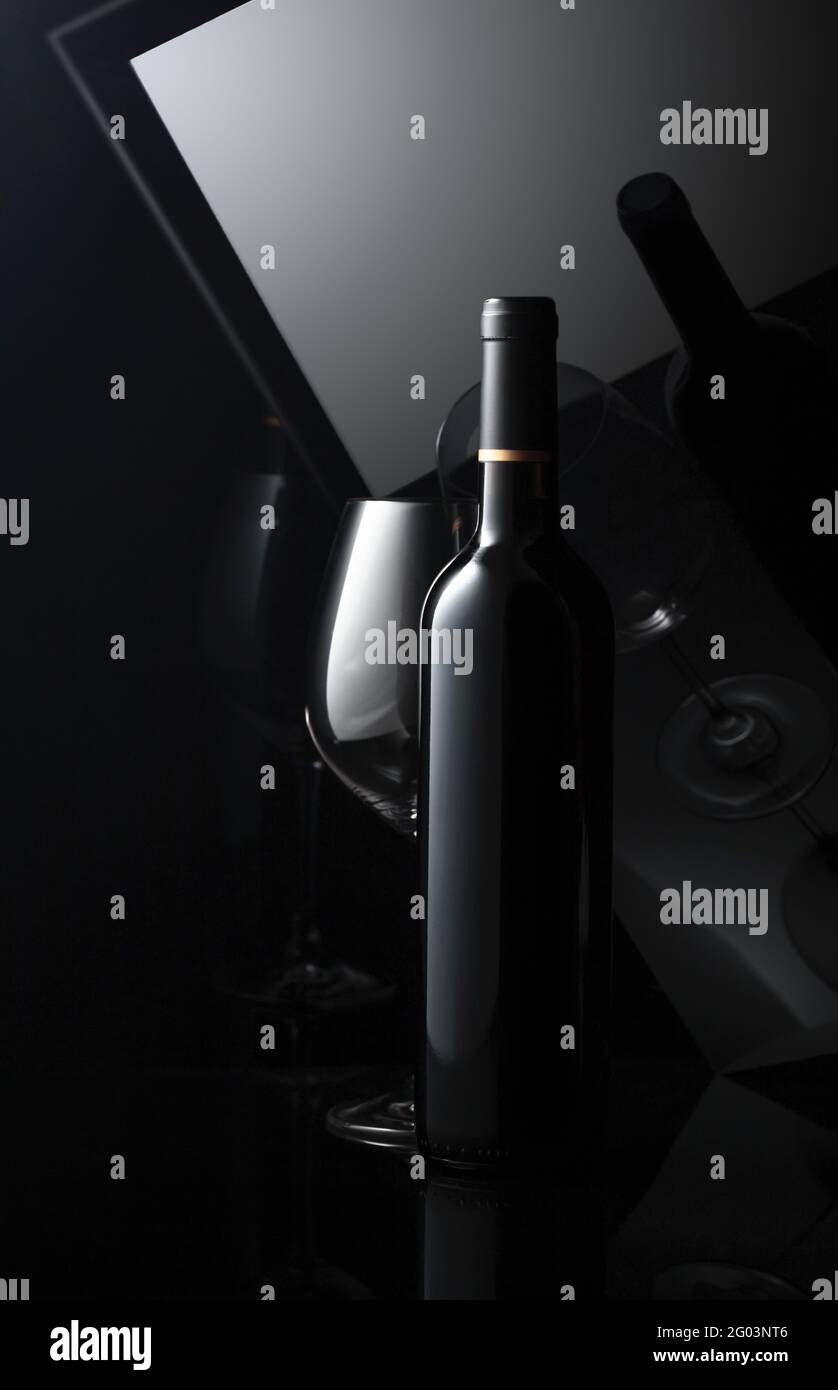 An unopened bottle of red wine with a reflection on the glossy black ...