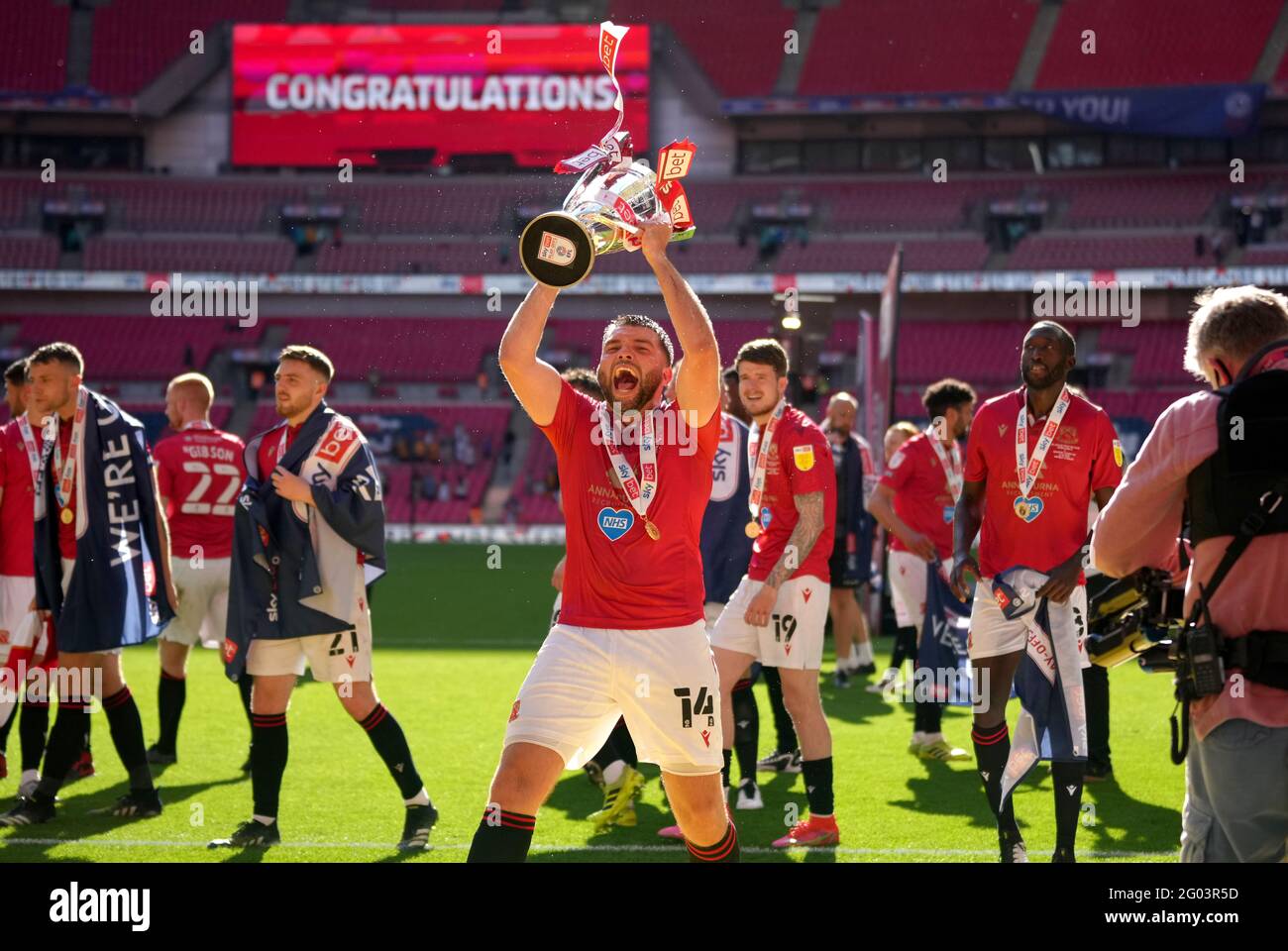 Morecambe's Alex Kenyon (centre) celebrates with the trophy after the ...