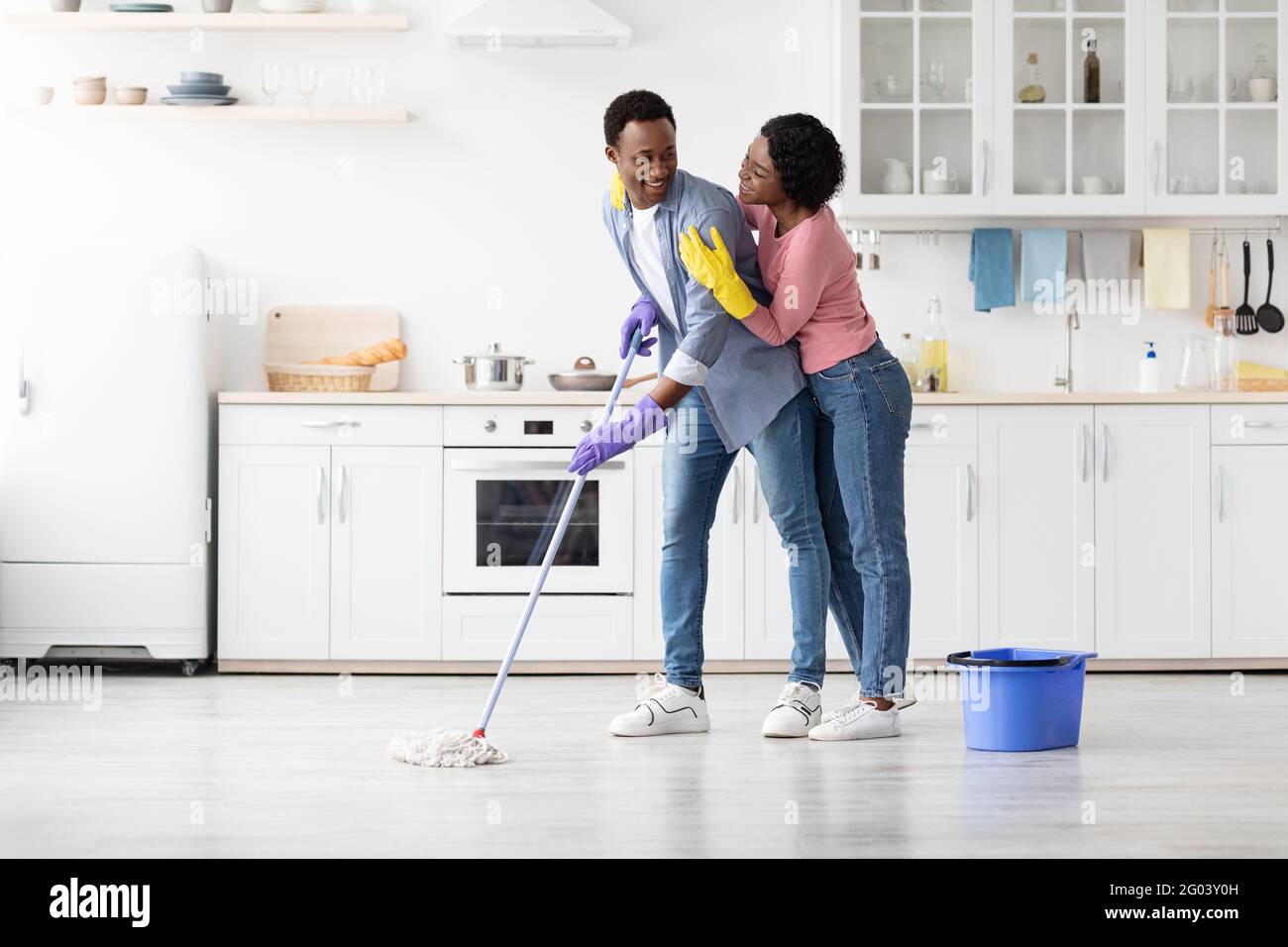 Joyful african american couple cleaning house together Stock Photo - Alamy