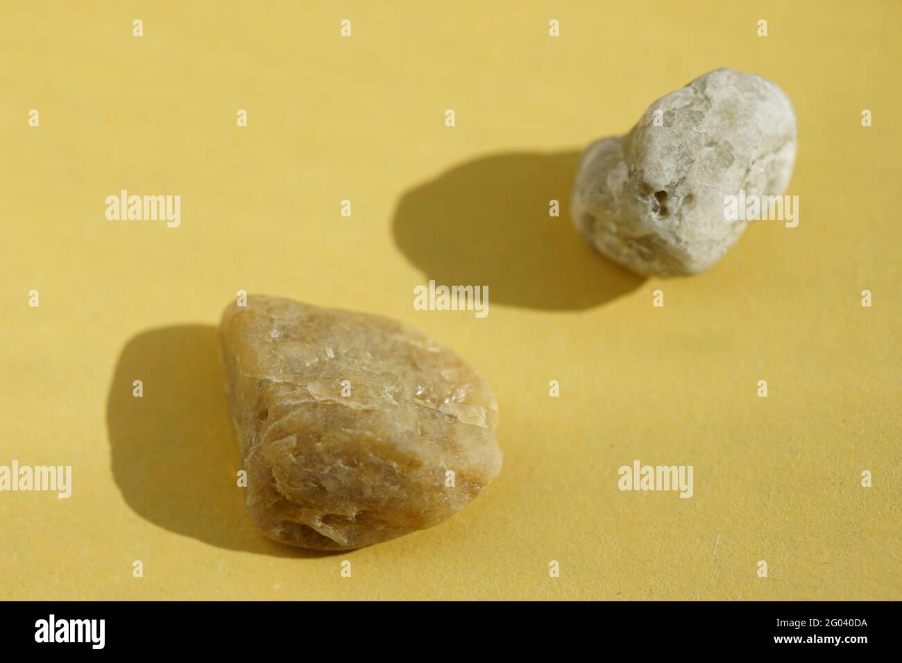 Beige and grey pebble stones at yellow sunny table Stock Photo - Alamy