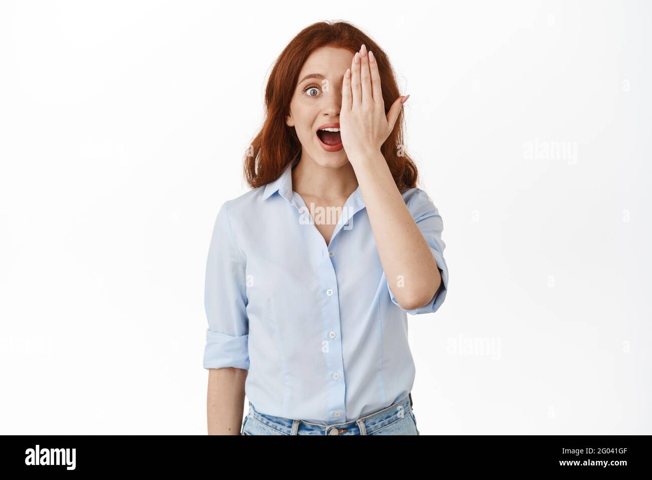 Excited and surprised redhead woman gasp from amazement, hide one half ...