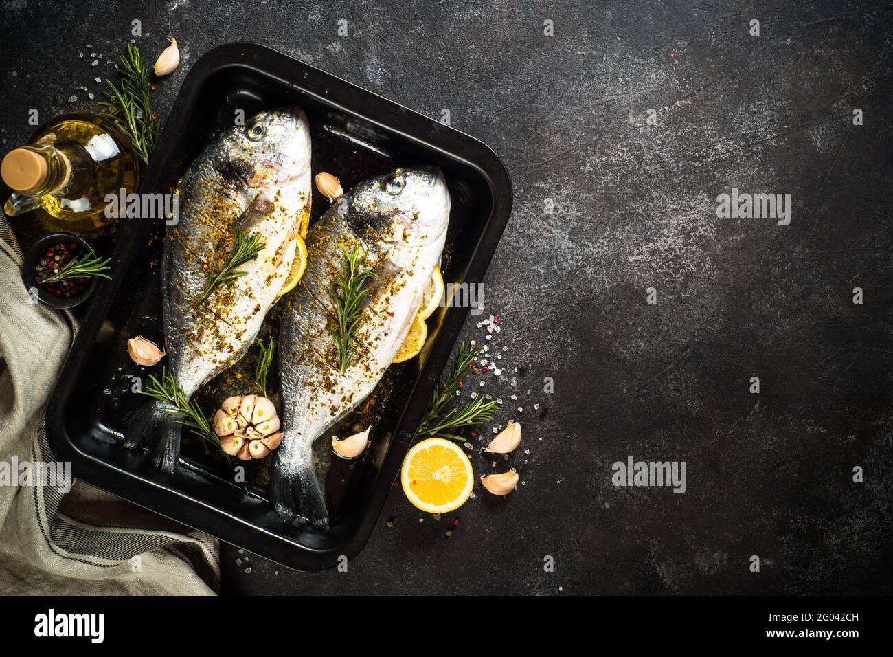 Raw fish dorado in baking sheet at black stone table Stock Photo - Alamy