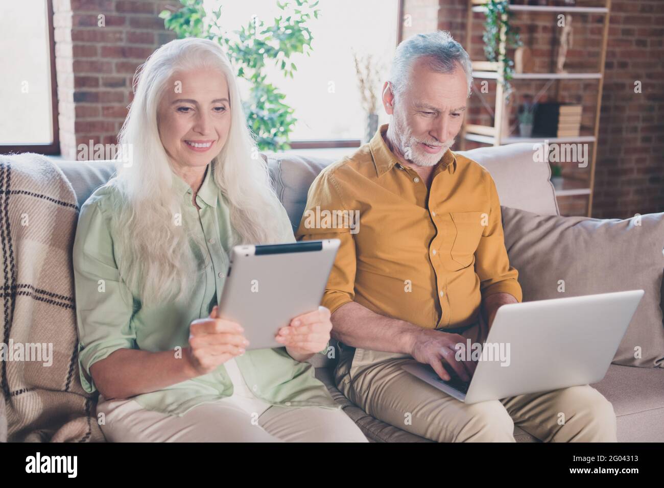 Portrait of attractive elderly cheerful grey-haired couple sitting on ...