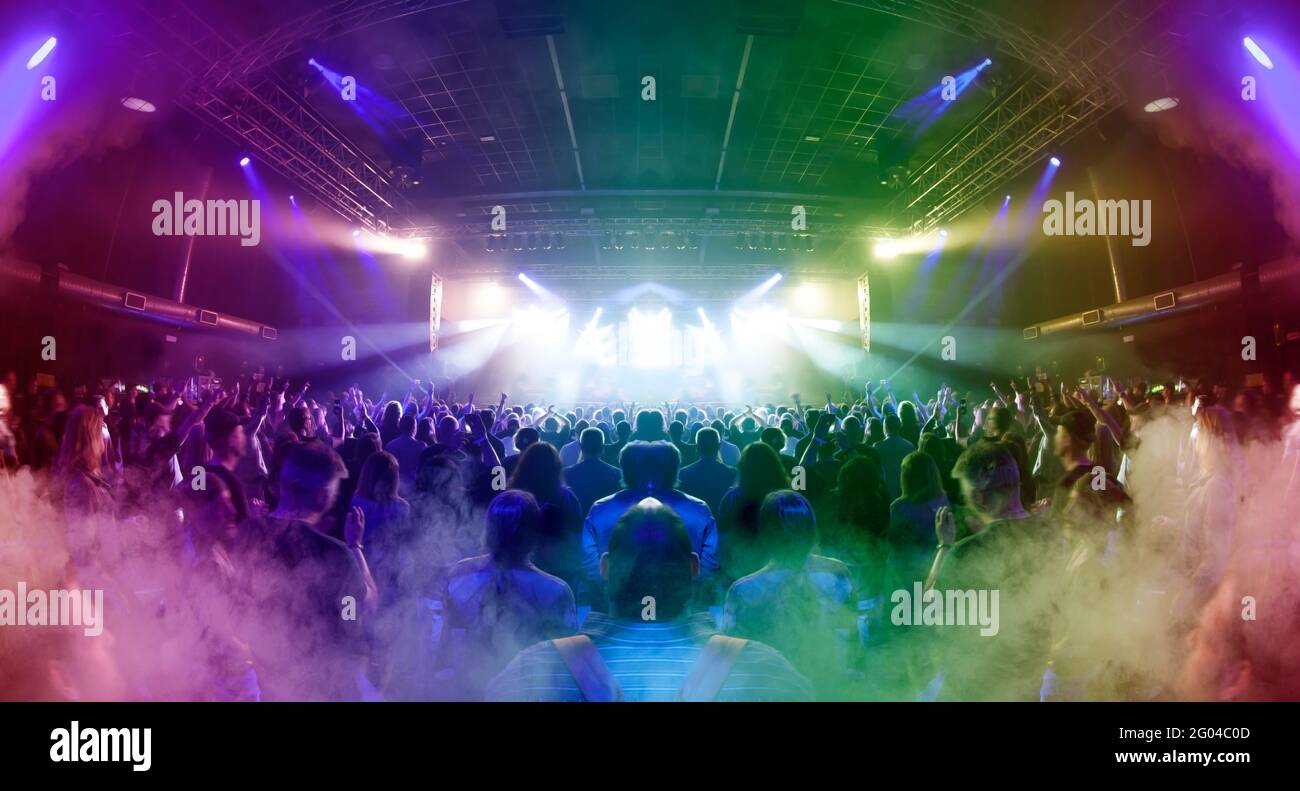 Concert crowd inside a venue, lens flare and smoke are visible Stock ...