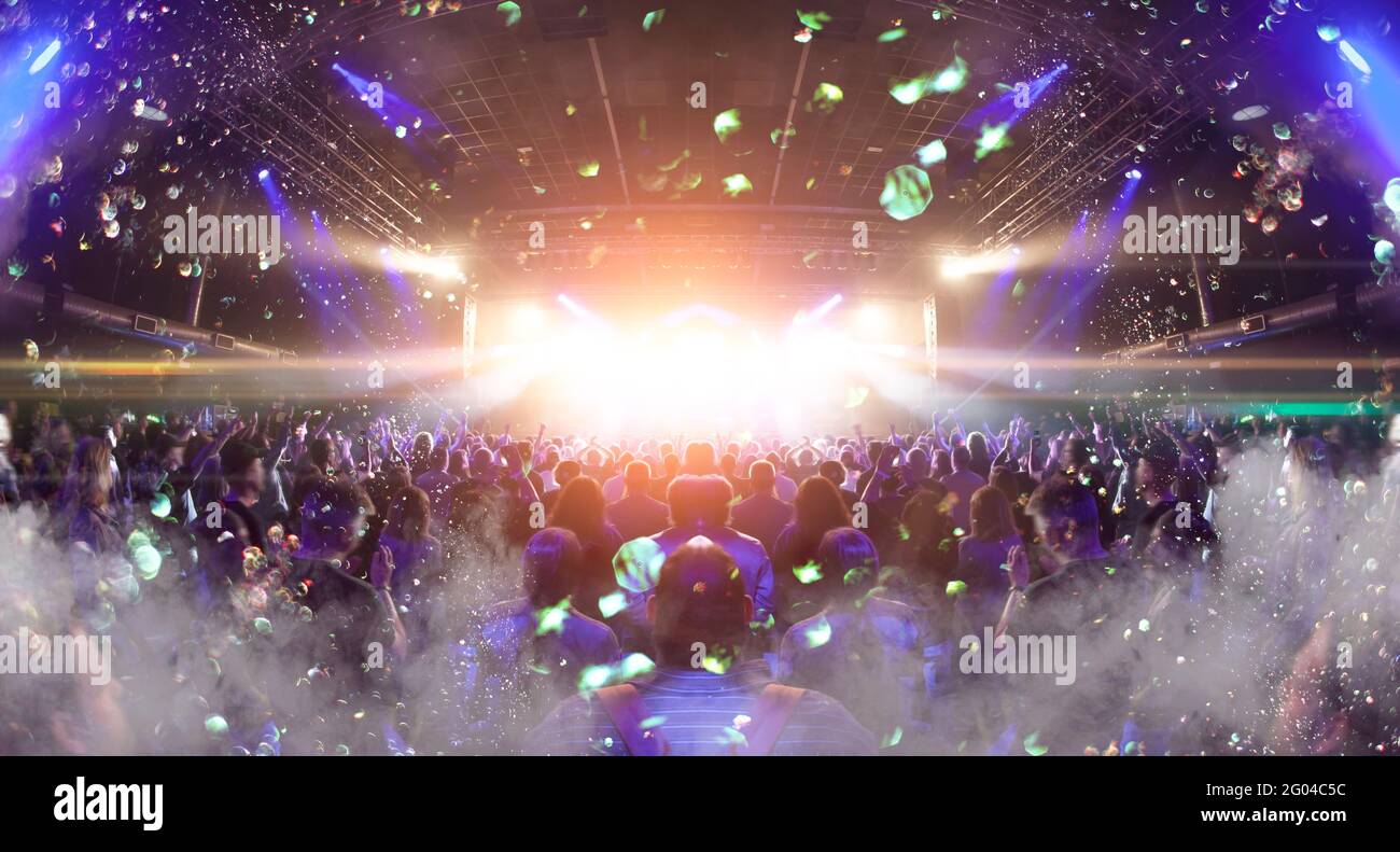 Concert crowd inside a venue, lens flare and smoke are visible Stock ...