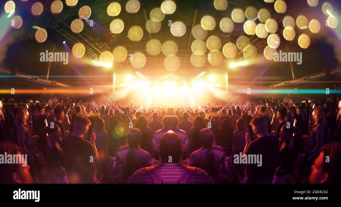 Concert crowd inside a venue, lens flare and smoke are visible Stock ...