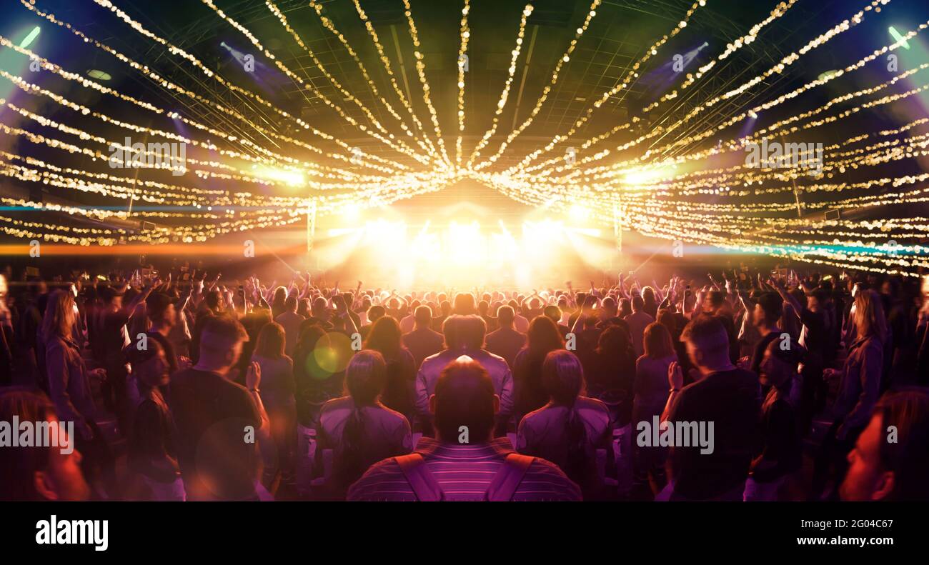 Concert crowd inside a venue, lens flare and smoke are visible Stock ...