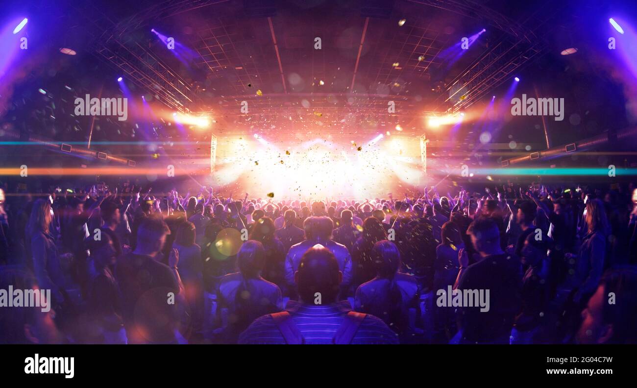 Concert crowd inside a venue, lens flare and smoke are visible Stock ...