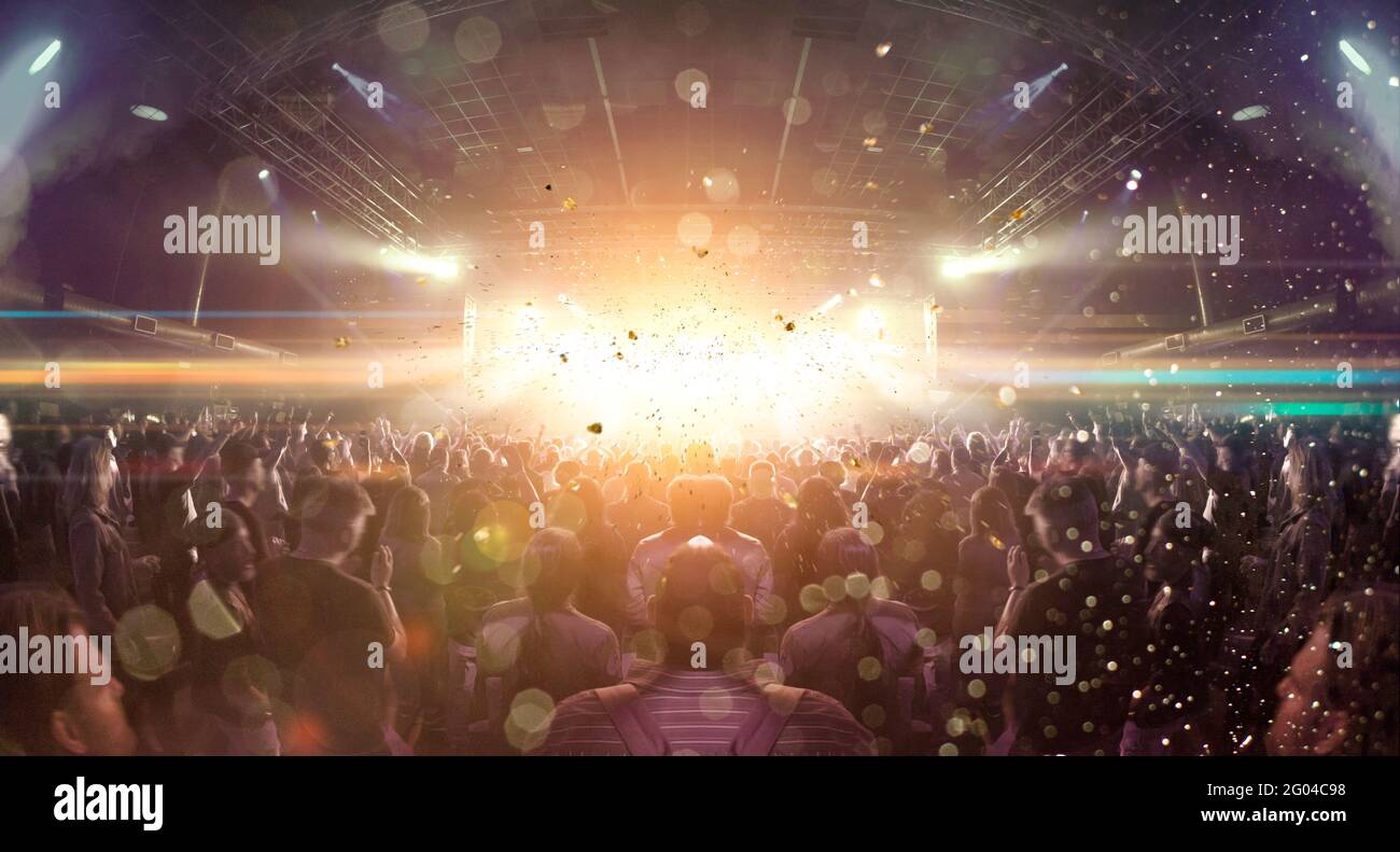 Concert crowd inside a venue, lens flare and smoke are visible Stock ...
