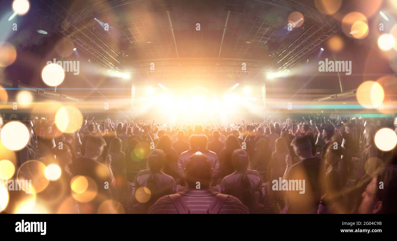Concert crowd inside a venue, lens flare and smoke are visible Stock ...