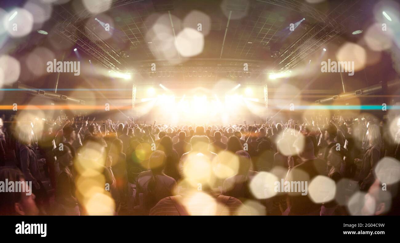Concert crowd inside a venue, lens flare and smoke are visible Stock ...