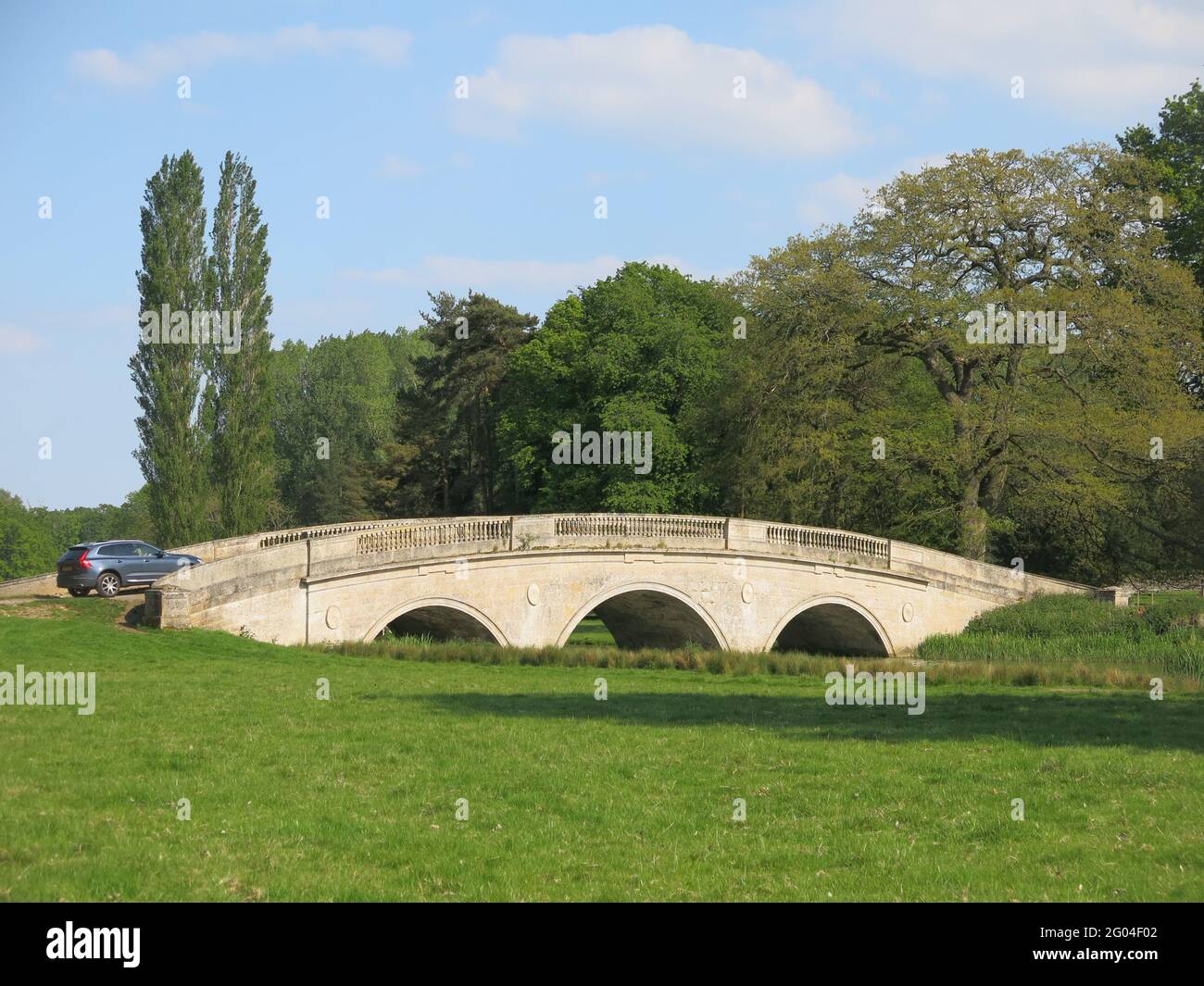 Blue Volvo car crossing the Grade II listed, three arched, limestone ...