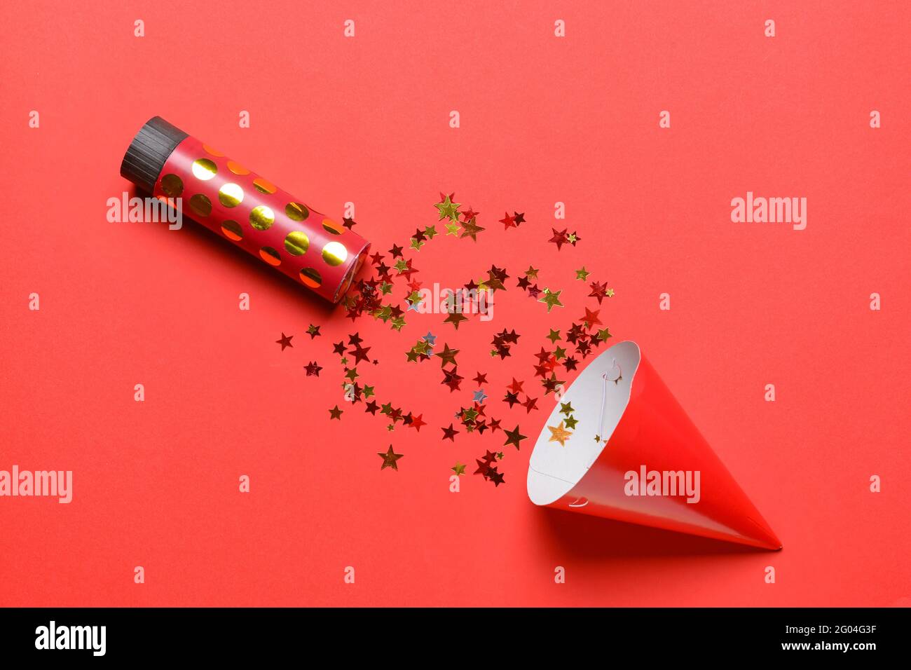 Party popper, hat and confetti on color background Stock Photo - Alamy
