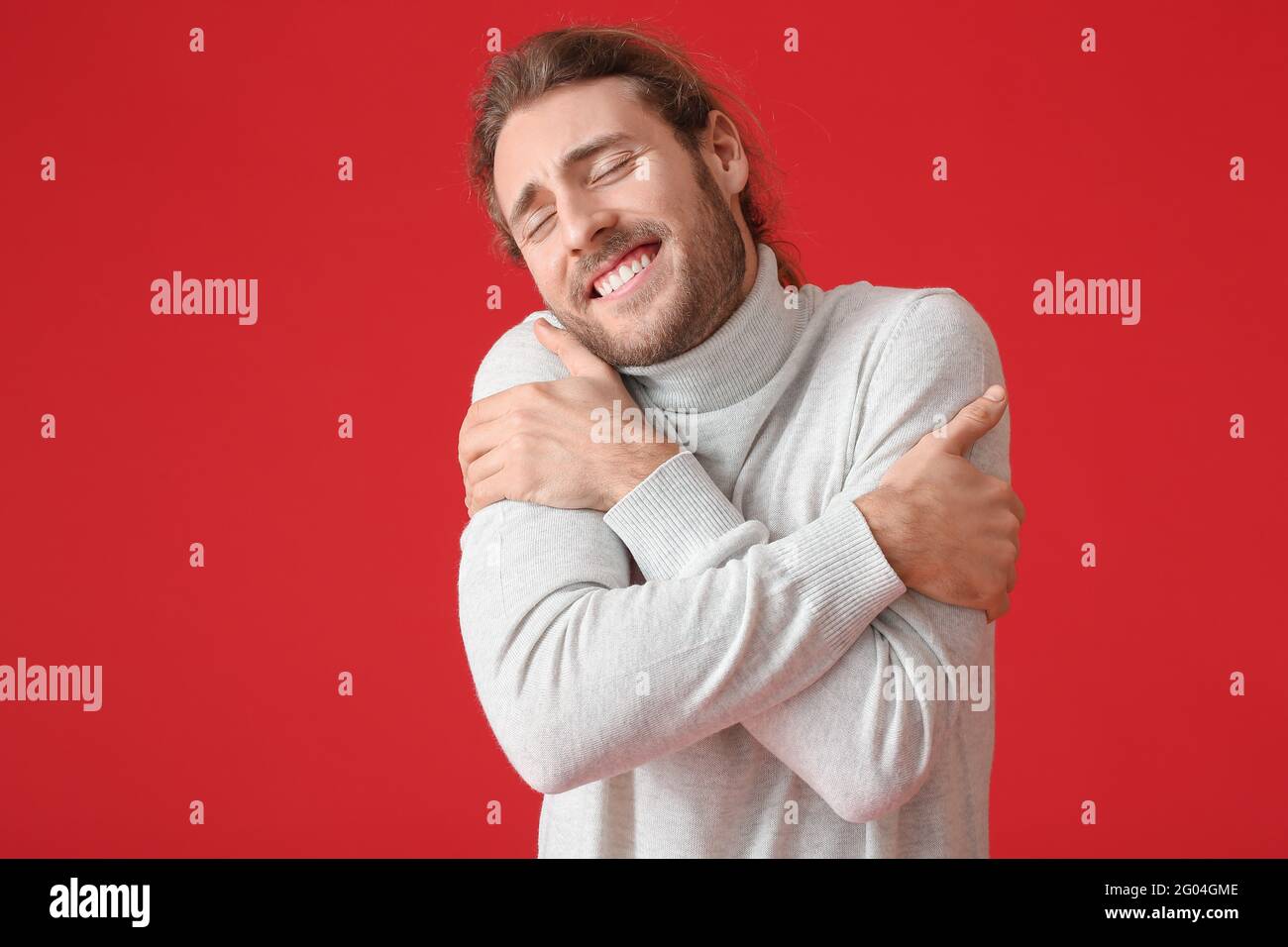 Young man hugging himself on color background Stock Photo - Alamy