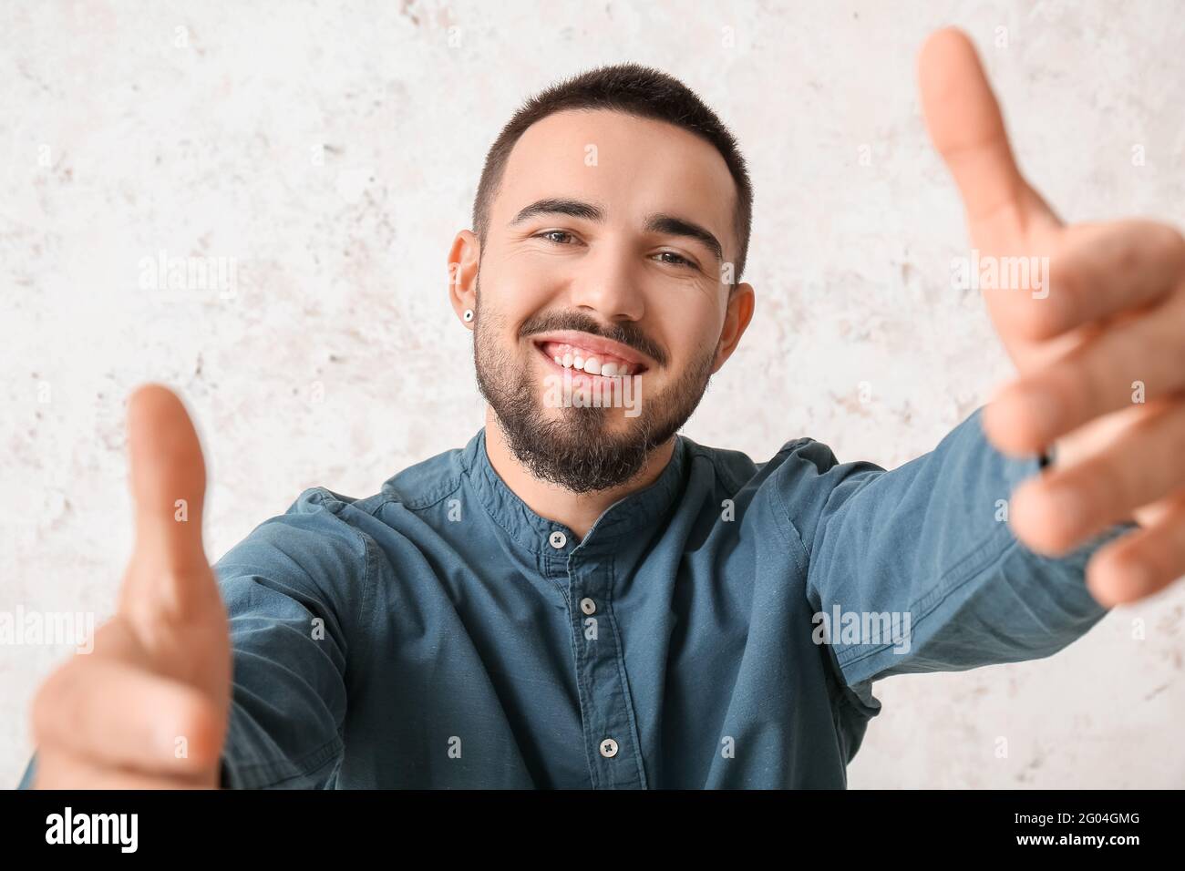 Young man opening arms for hug on light background Stock Photo - Alamy
