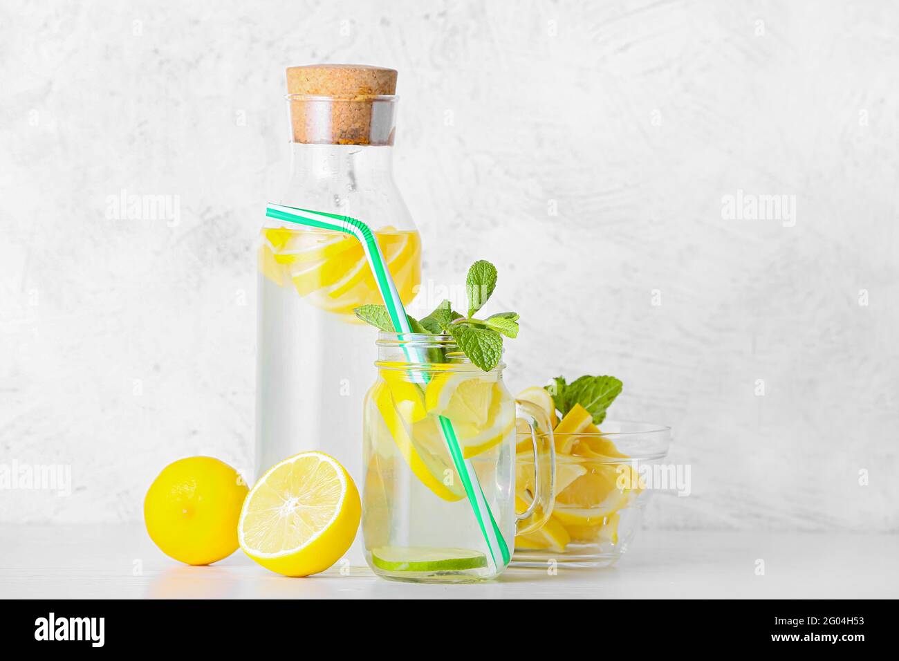 Bottle and mason jar of tasty cold lemonade on light background Stock ...