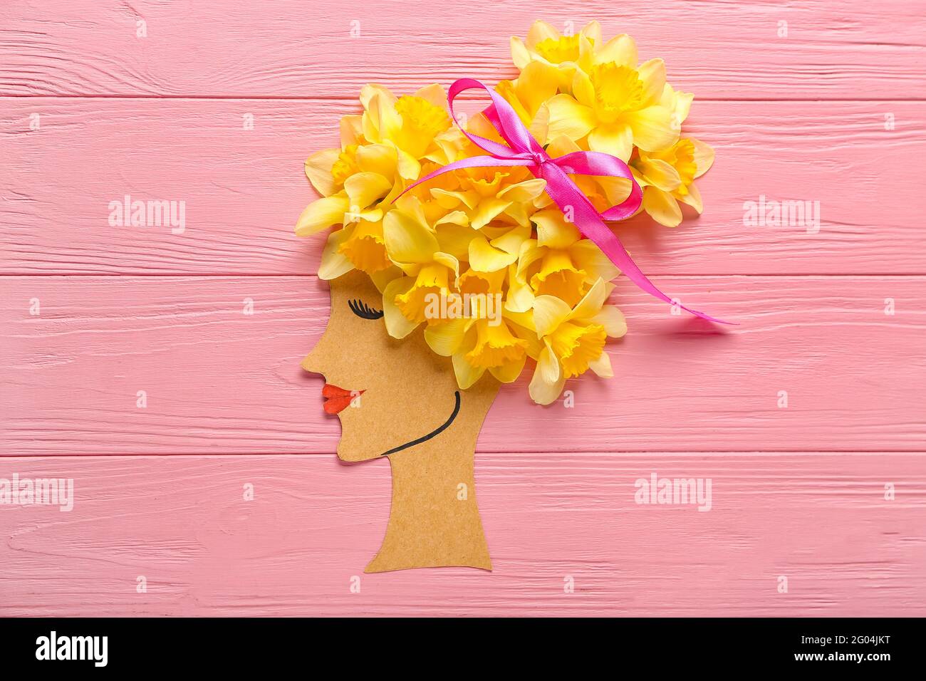 Paper female figure with beautiful daffodils on color wooden background ...