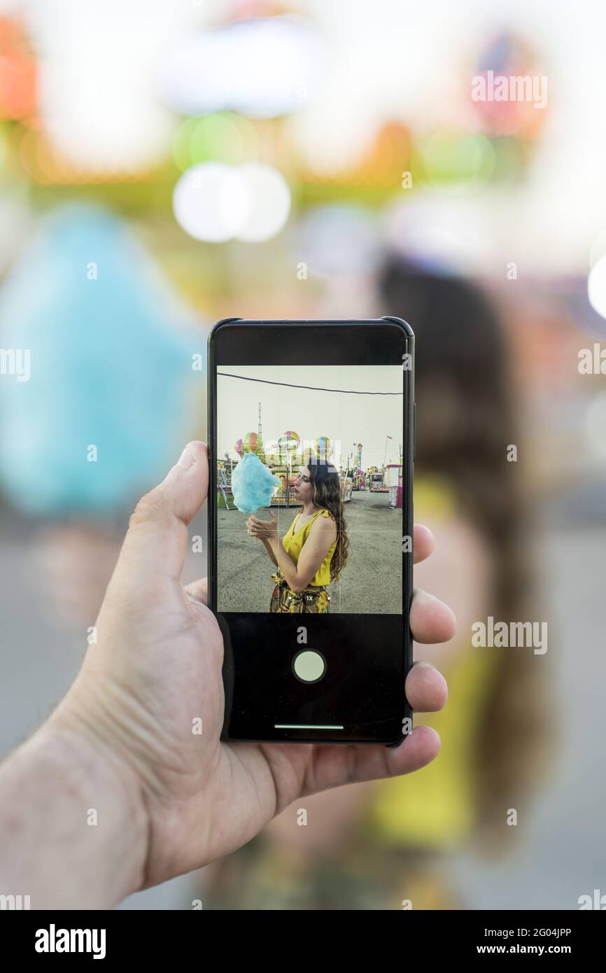 Vertical shot of a male taking a picture on his smartphone of a female ...
