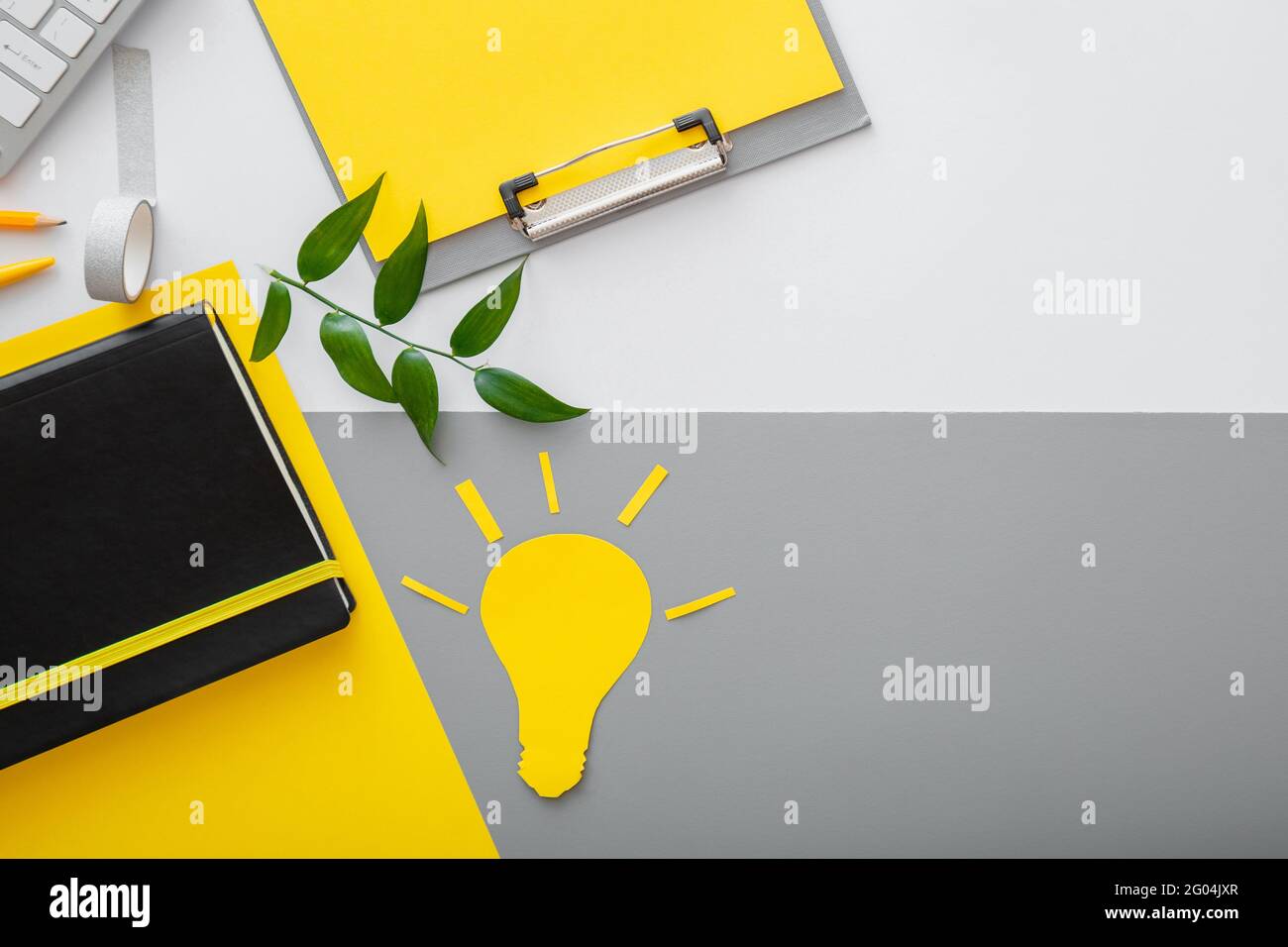 Yellow light bulb idea metaphor on desktop in workspace on gray table ...