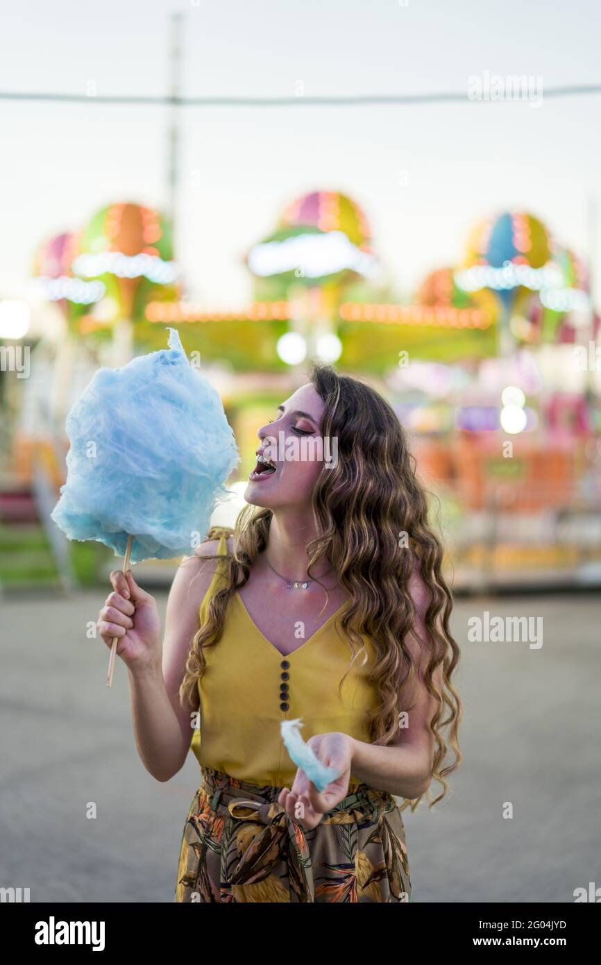 Vertical shot of a Caucasian female eating blue cotton candy in the ...