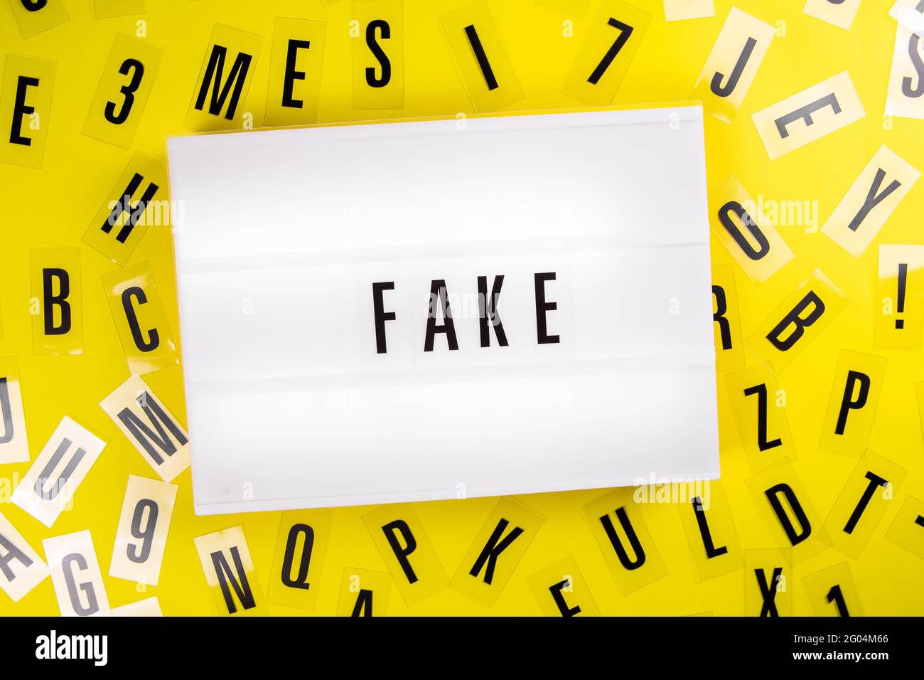 Lightbox text FAKE on yellow background with letters scattered ...