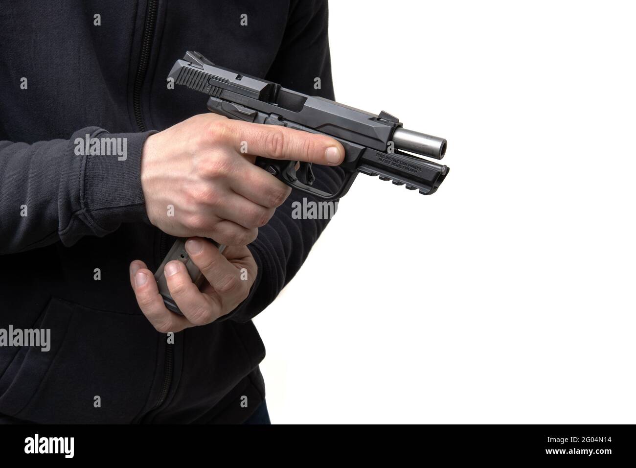 A man in dark clothes holds a pistol in his hands and reloads it ...