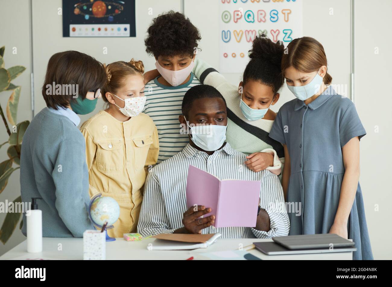 Portrait of diverse group of children and teacher wearing masks in ...