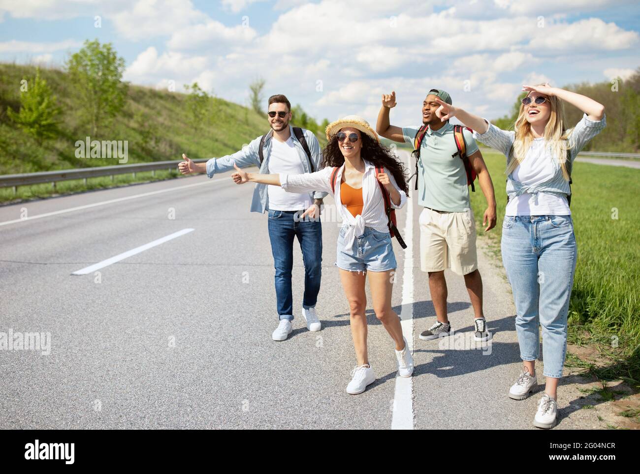 Group of young people standing on roadside, stopping car with ...