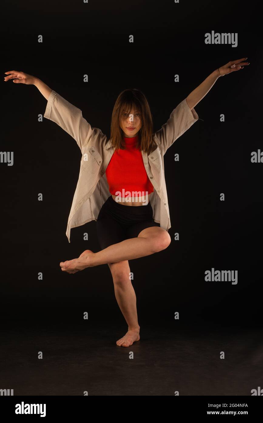 Pretty ballerina girl is doing a asymmetrical pose while balancing on ...