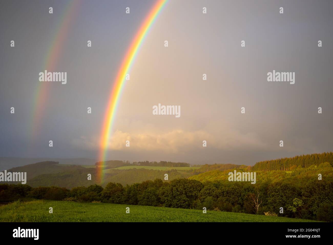 Beautiful partial rainbow on the blue sky above the green field and ...