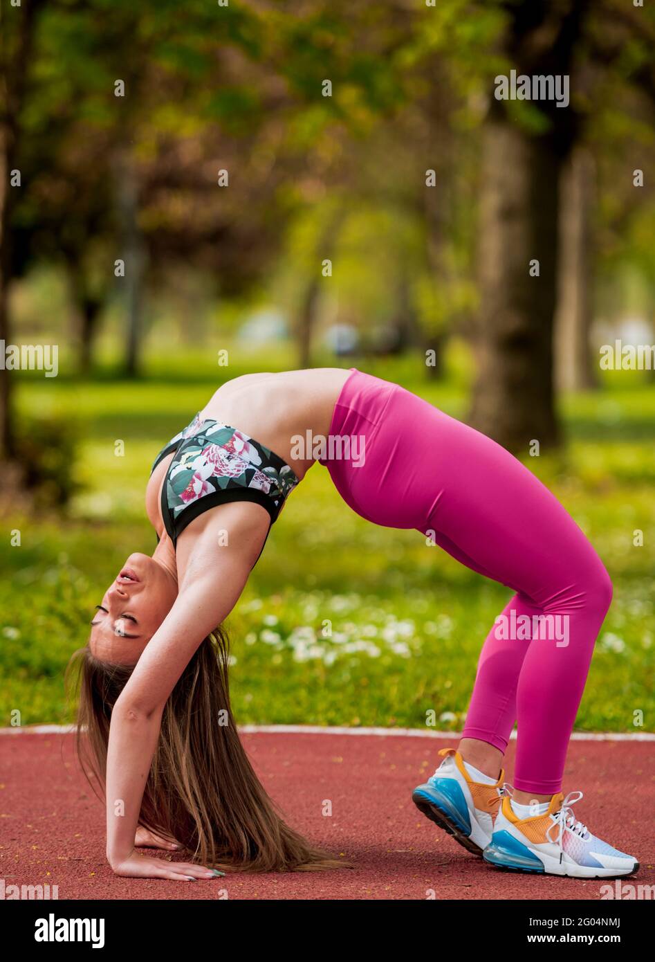 Sporty young Caucasian woman doing bridge stretching warm up before ...