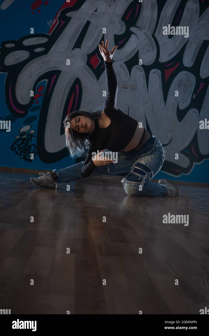 Female dancer in activewear squatting on the floor of modern dance ...