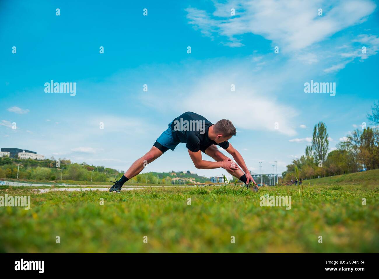 Strong man warming up at city park before jogging. Men stretching for ...