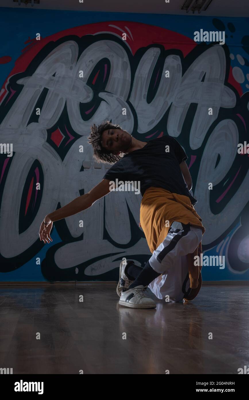 African American hip hop dancer (breakdancer) performing over graffiti ...
