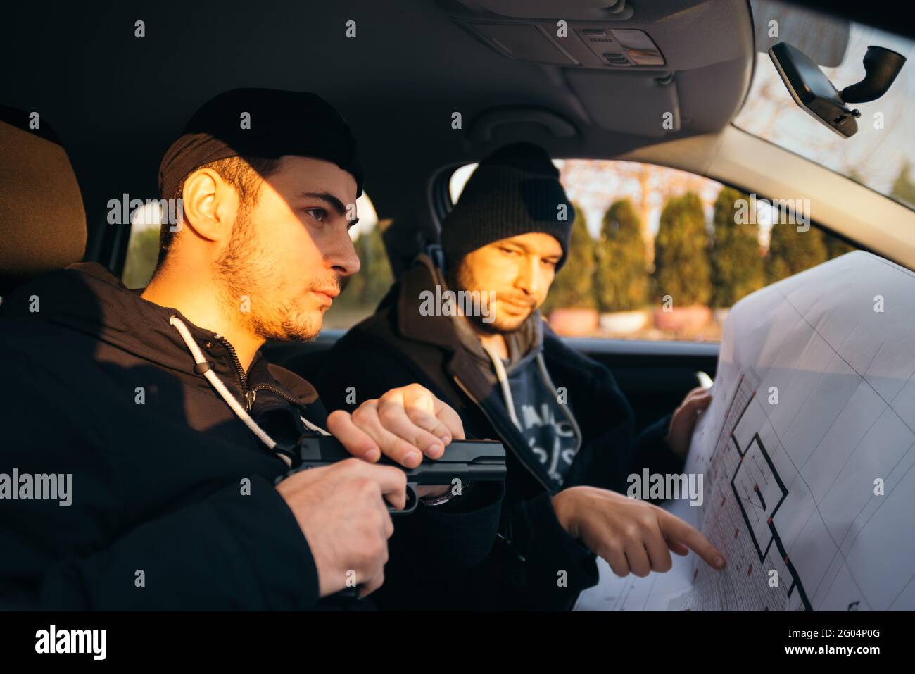 Two robbers planning and pointing on the blueprint(map) their objective ...