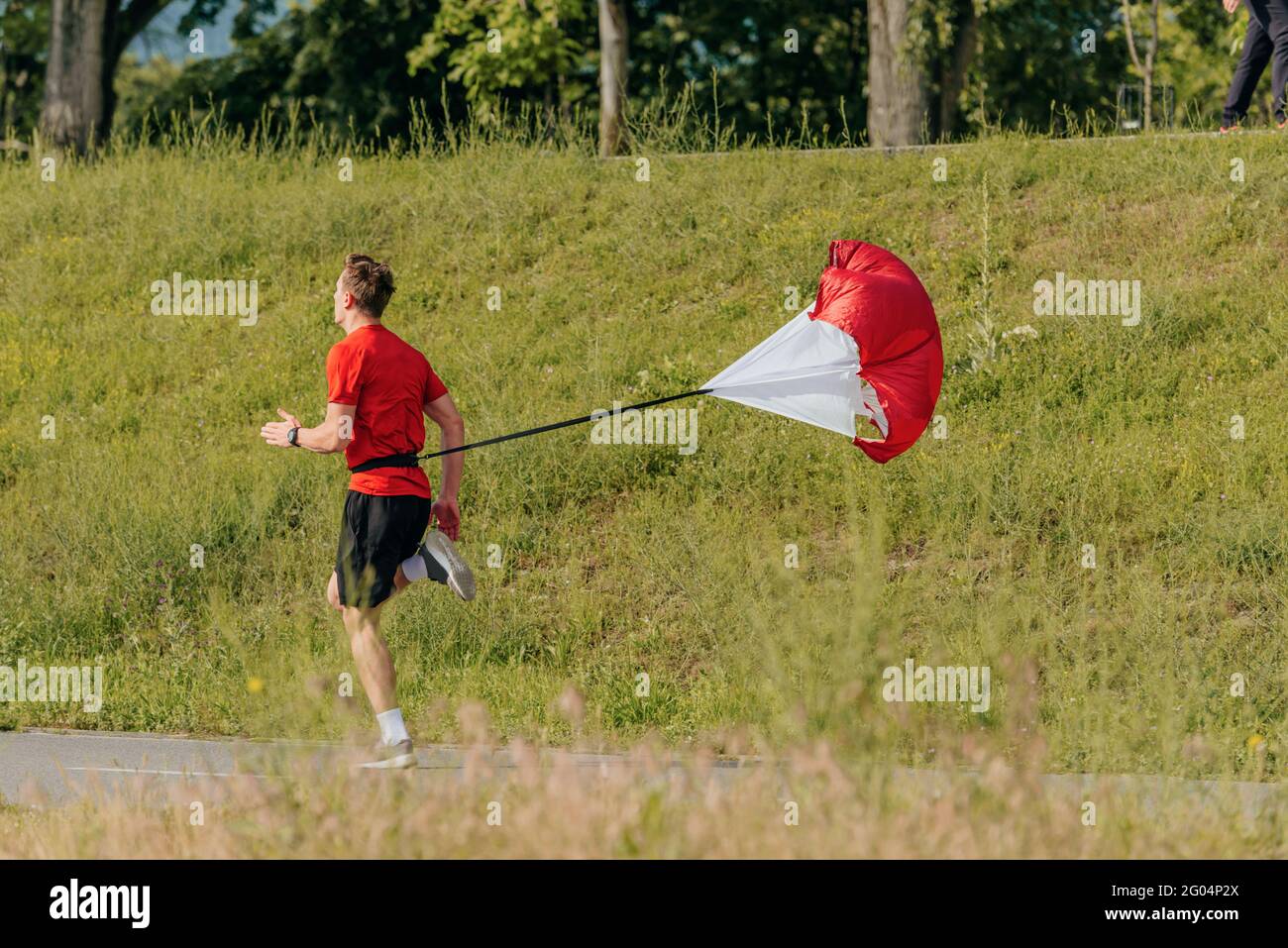 Side view of a strong man doing workout using resistance parachute ...