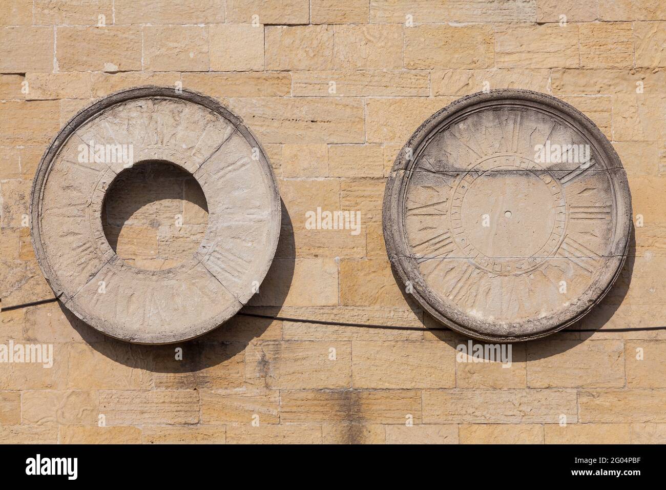 Watch dials attached to a stone wall Stock Photo - Alamy