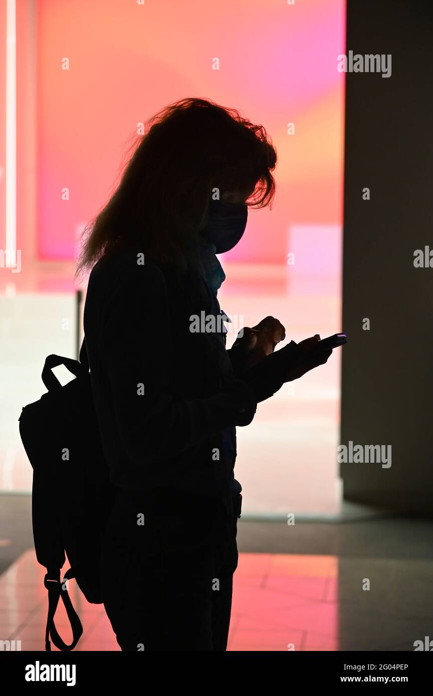 Silhouette of woman wearing a protective mask and scrolling on her ...