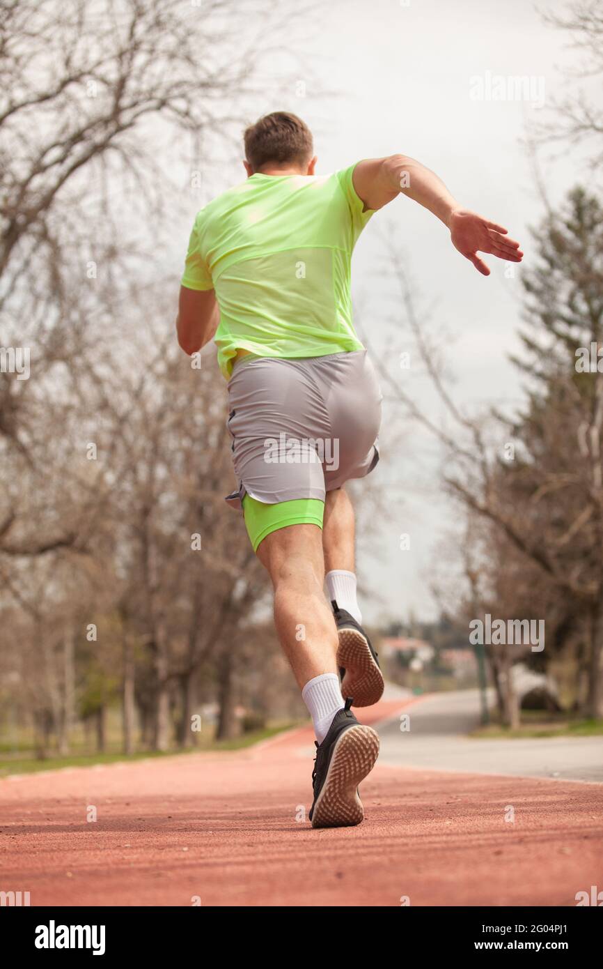 Strong male is running on the running trail close up from the back ...