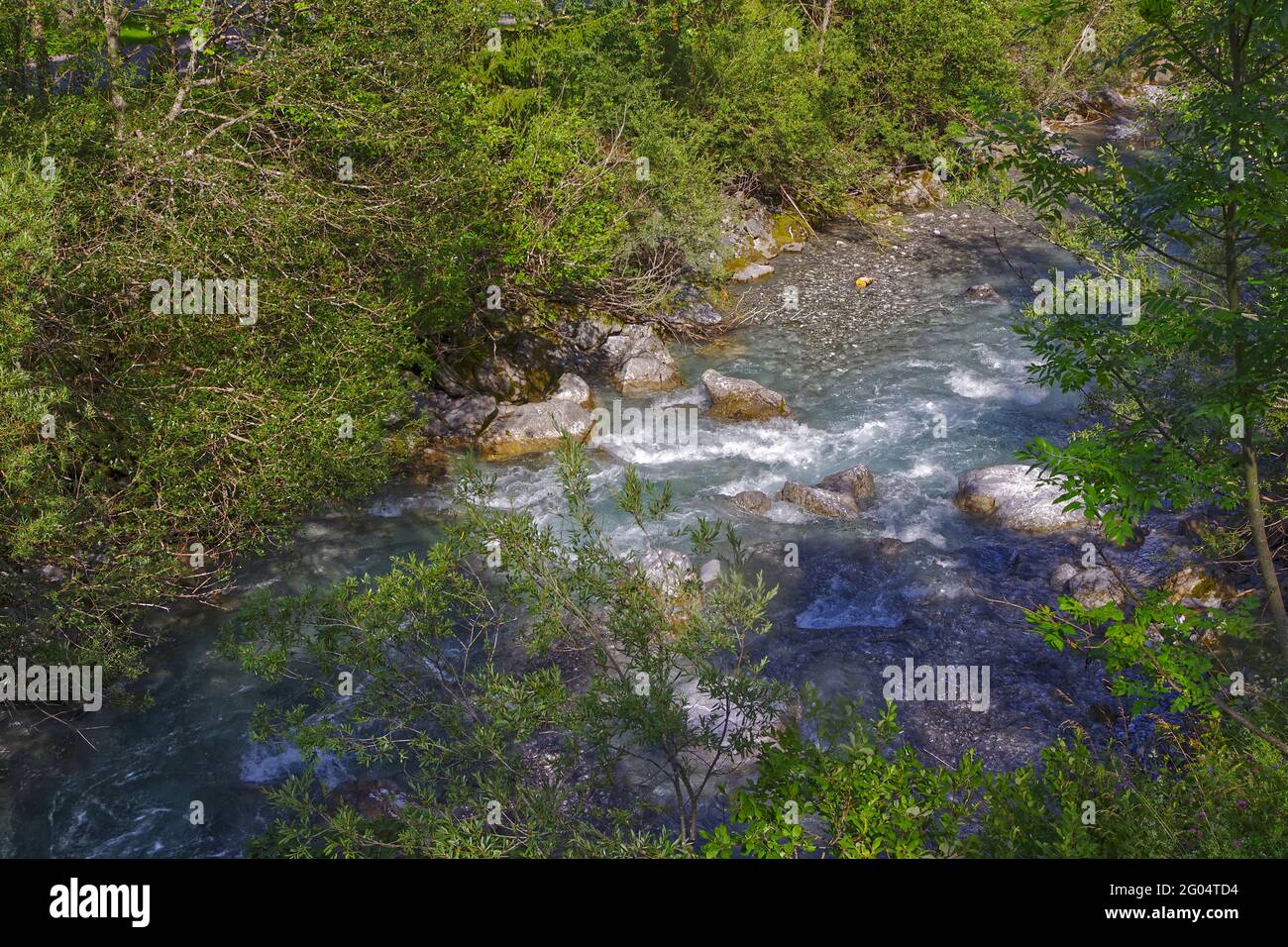 Flowing water of a shallow river surrounded by green plants in Austria ...