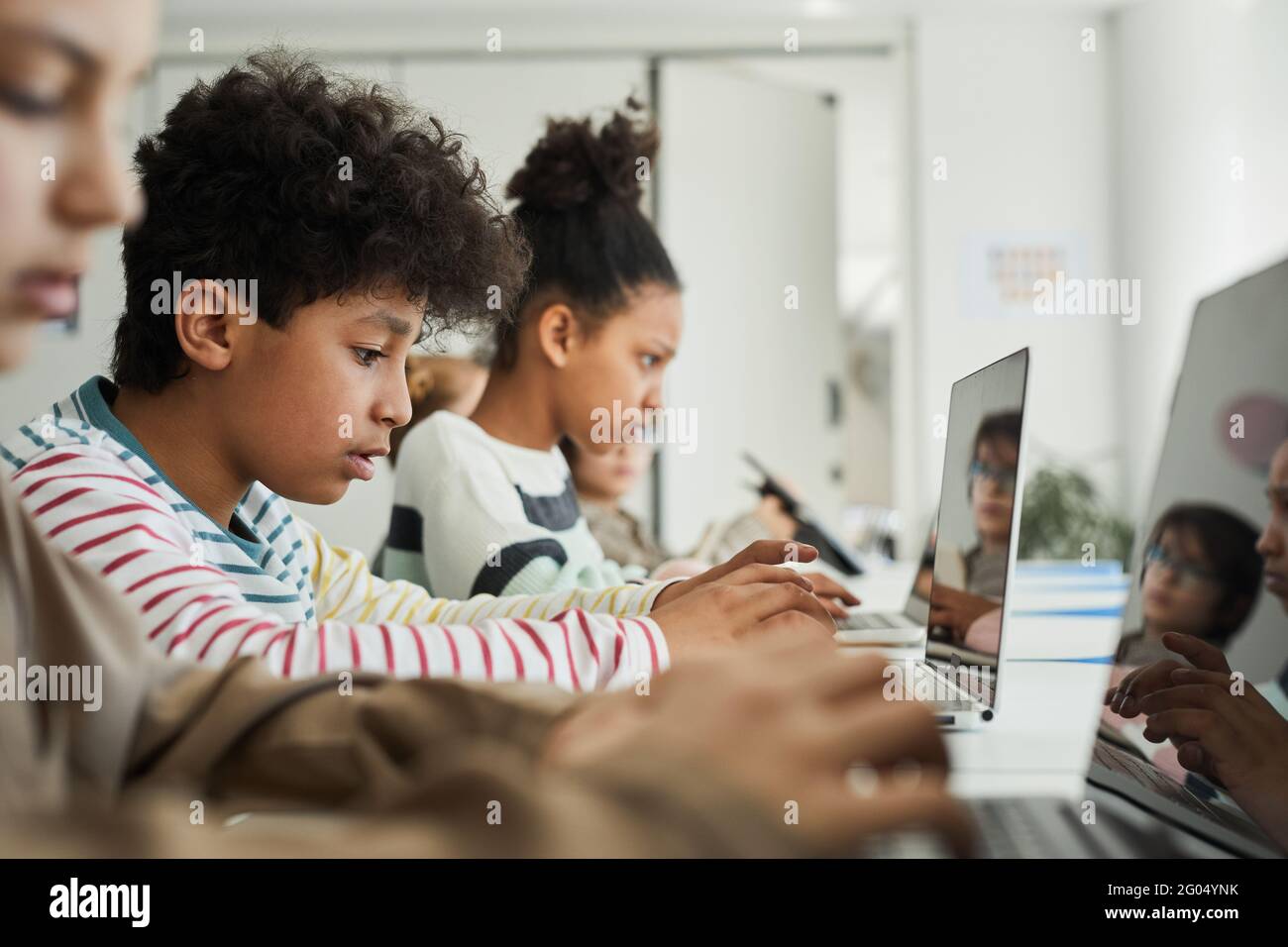 Side view at diverse group of children sitting in row at school ...
