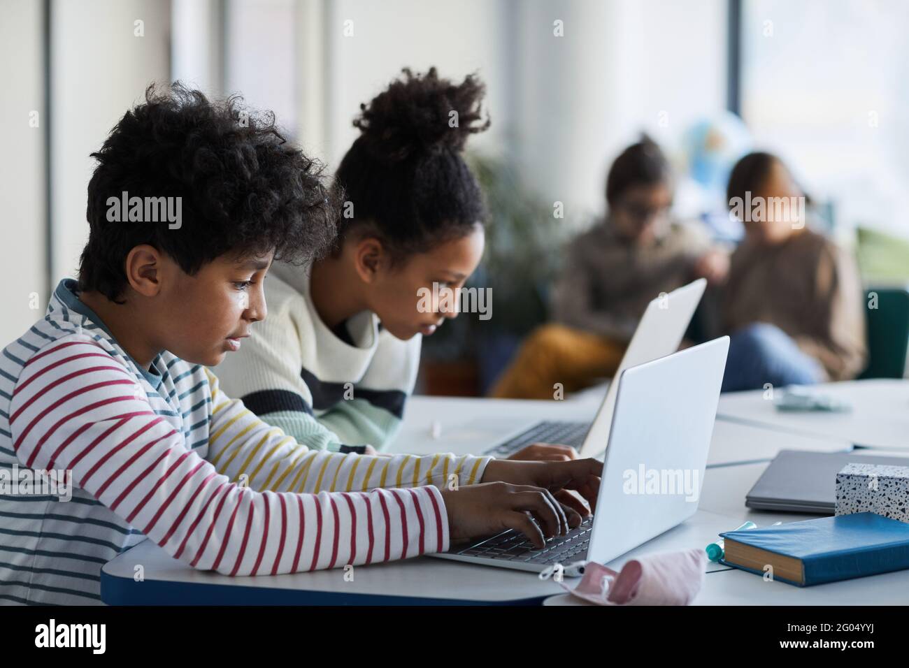 Side view portrait of two children using computers in modern school ...