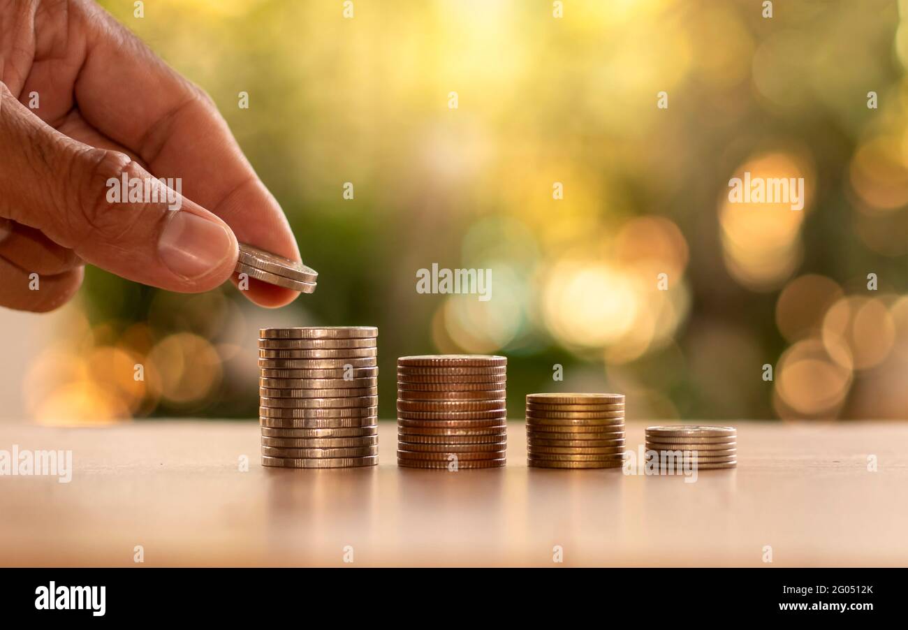 Human hands holding coins and piles of coins on wooden floor financial ...