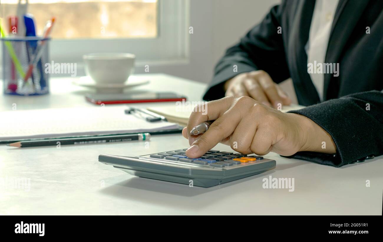 Close-up of women using calculators and note-taking, accounting reports ...