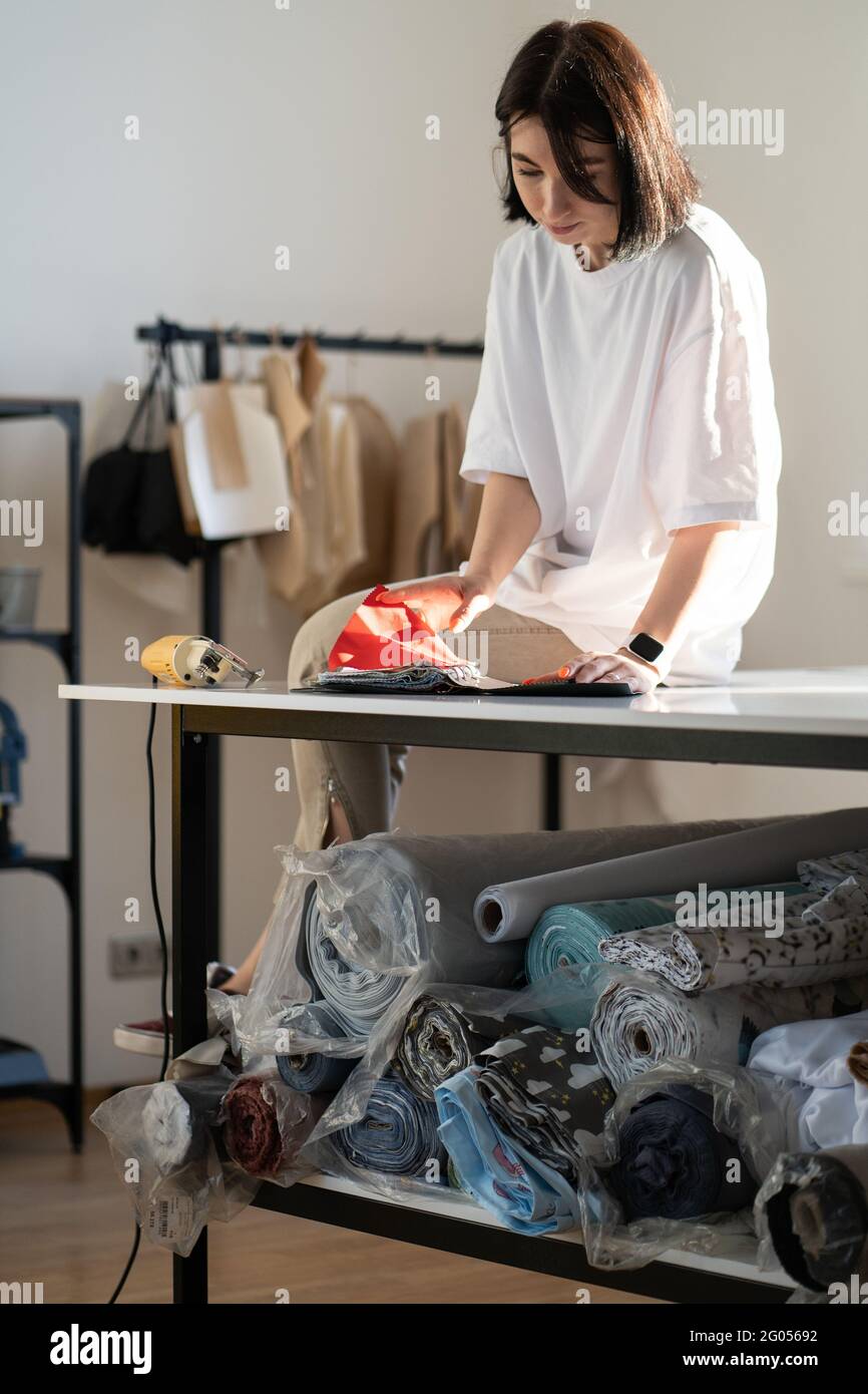 Young woman dressmaker choose fabric of cloth catalog for clothes ...