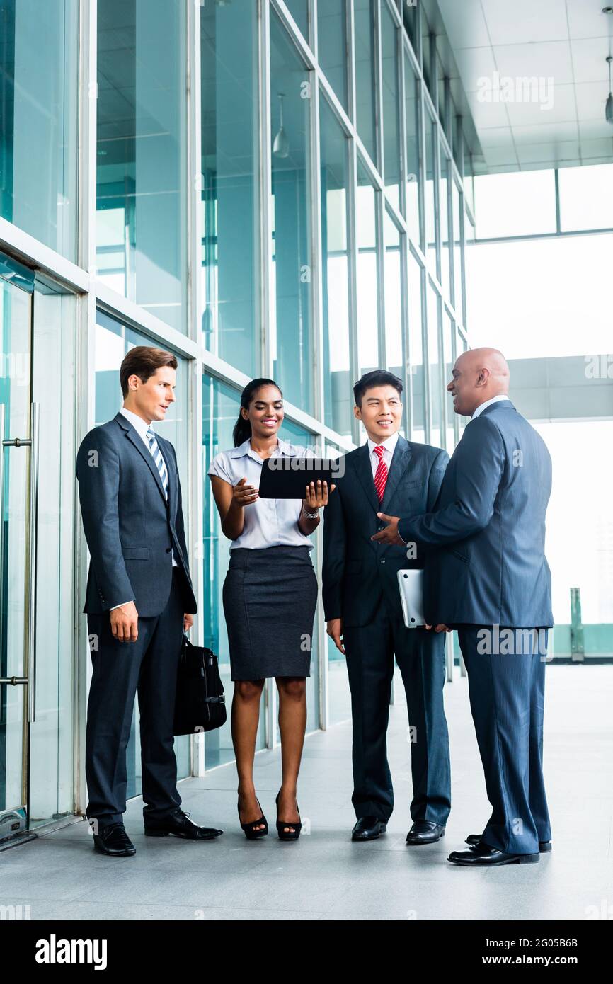 Pan Asian and Caucasian business team looking at tablet computer ...