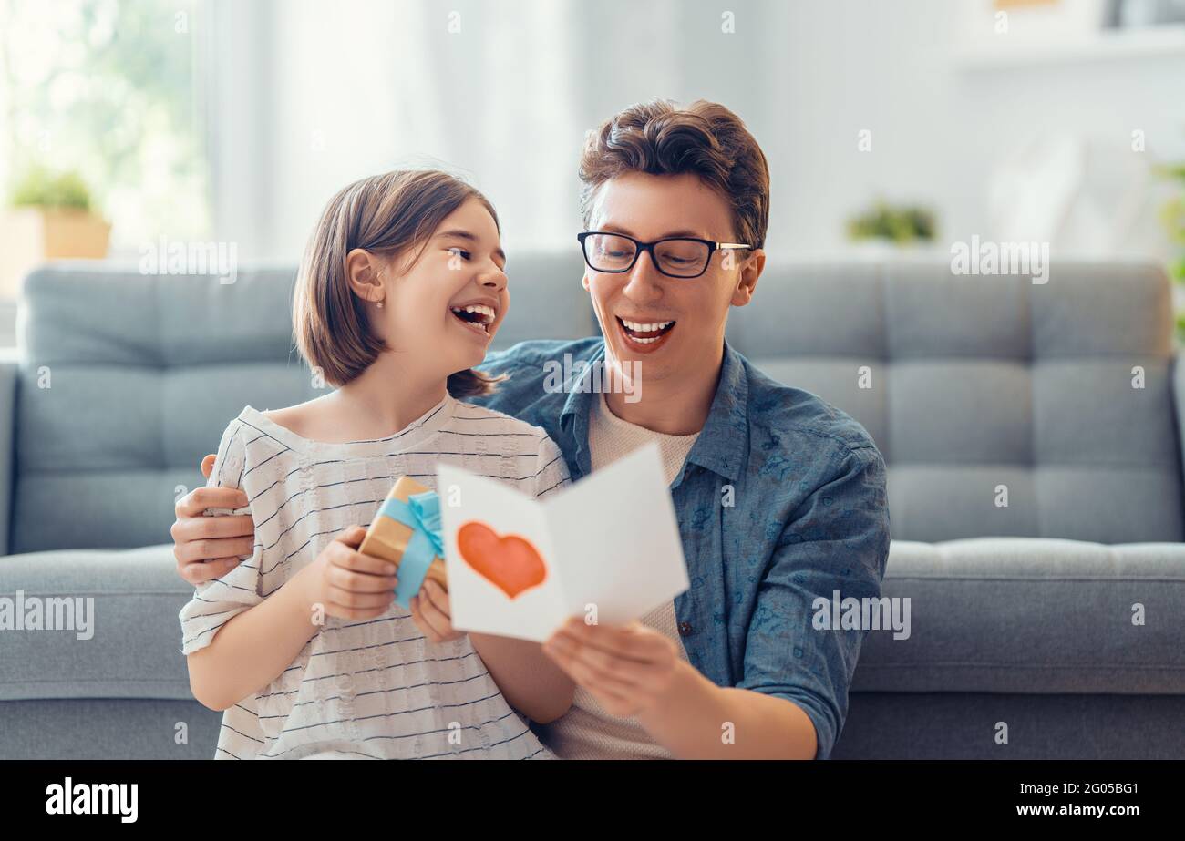 Child daughter is congratulating her father and giving him postcard ...