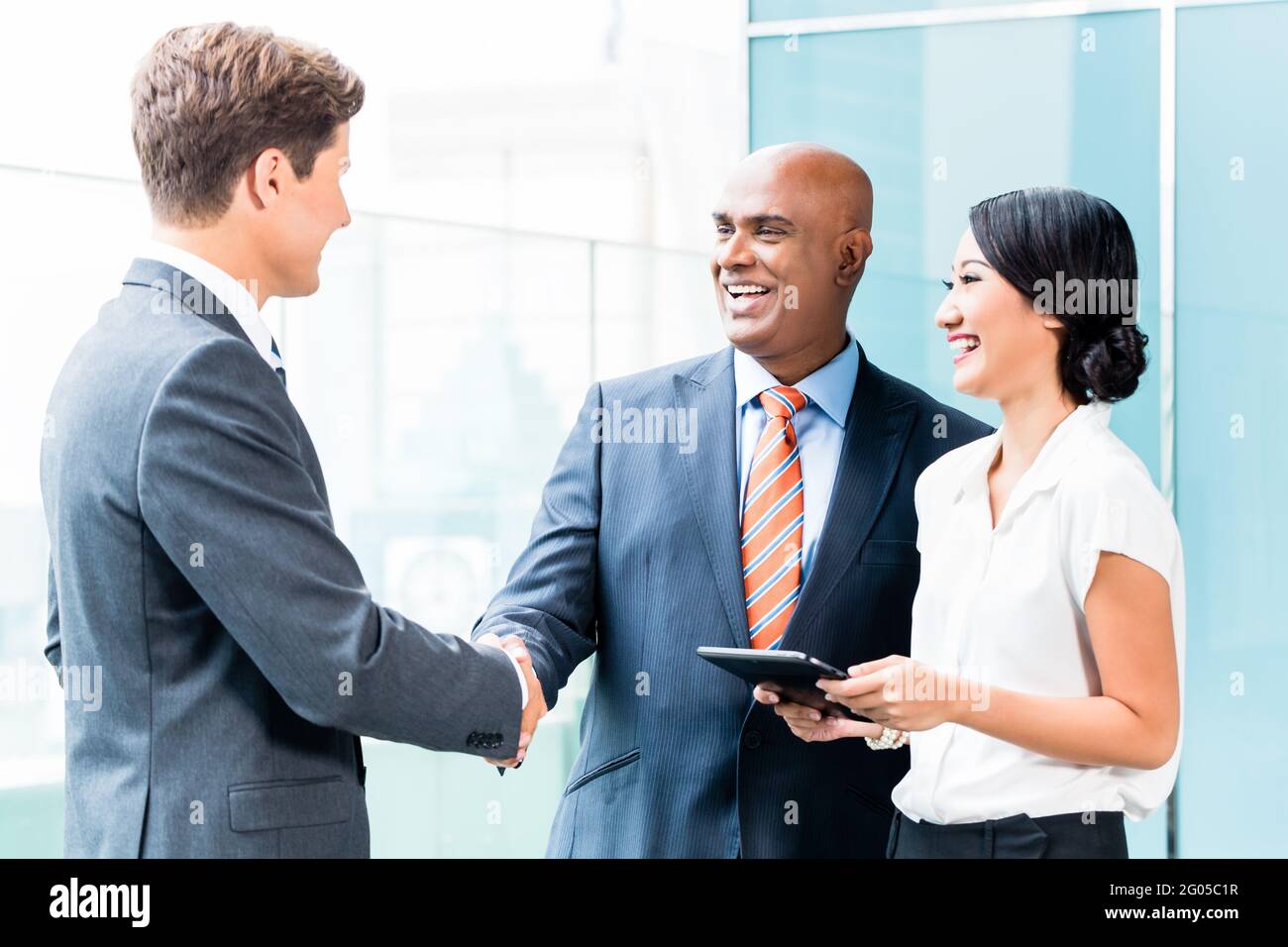 Indian CEO and Caucasian executive having business handshake in front ...
