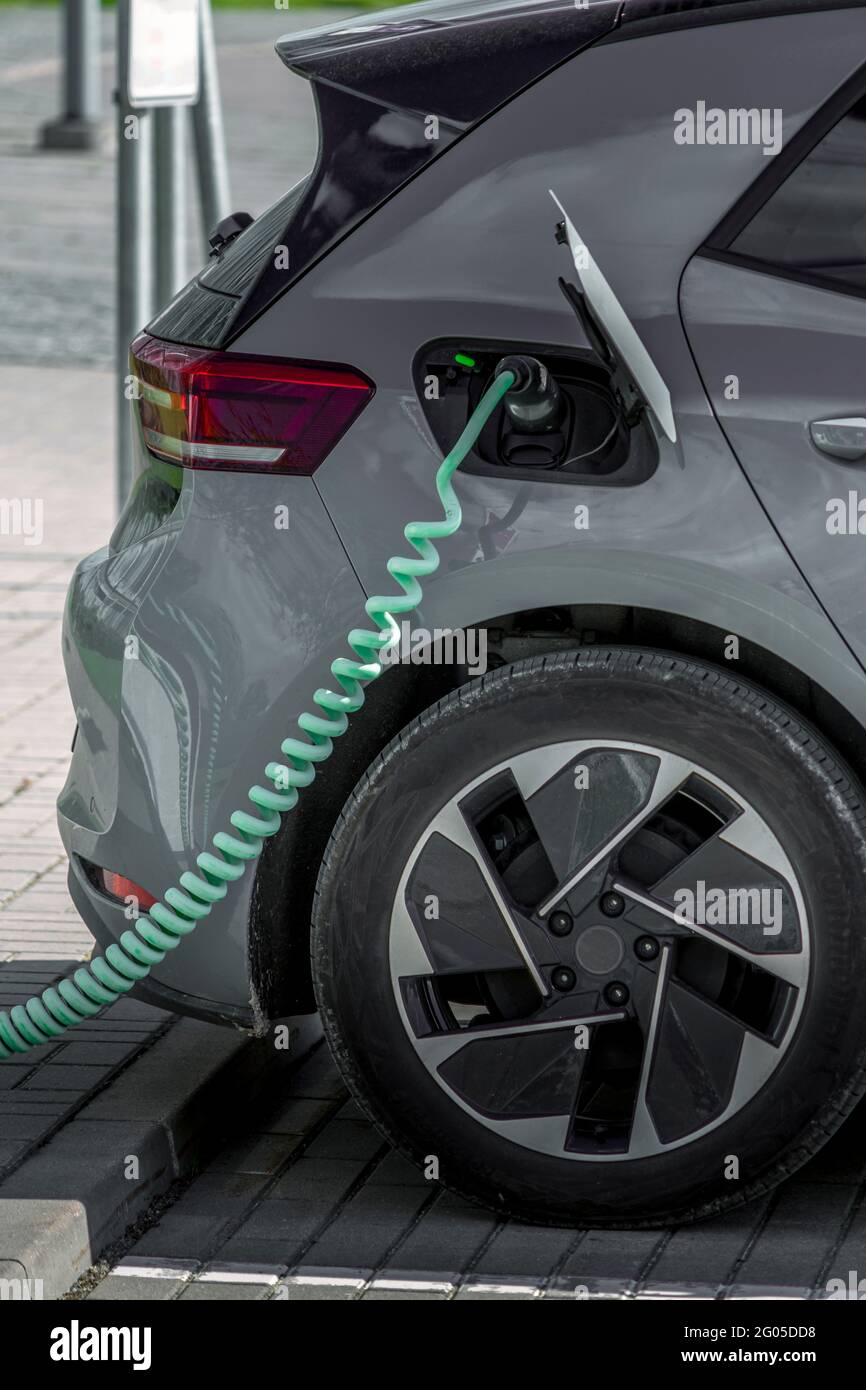 Close up of power supply plugged into gray electric car being charged ...