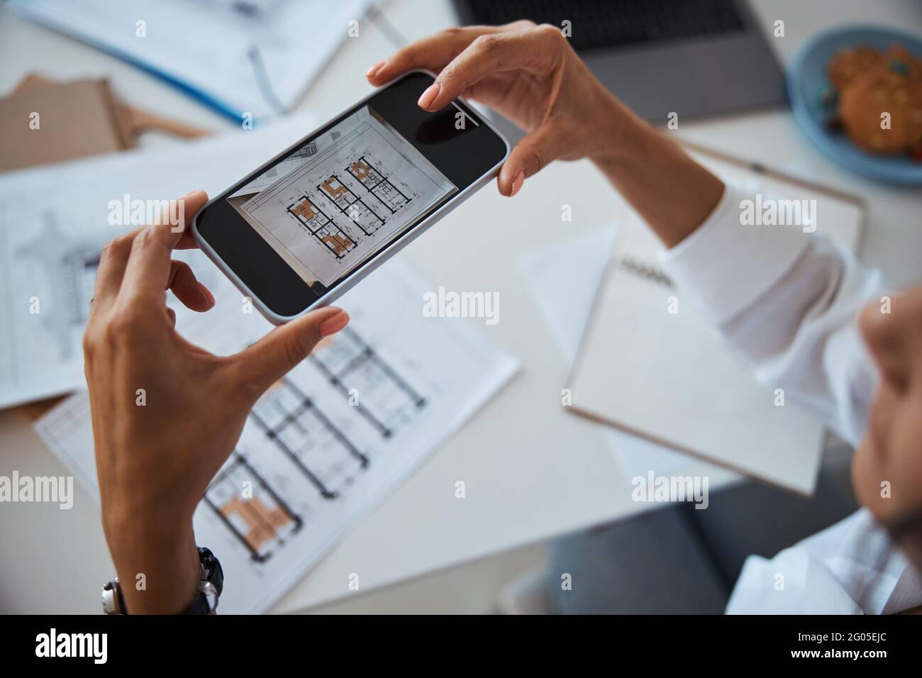Female architect taking picture of building plan at work Stock Photo ...